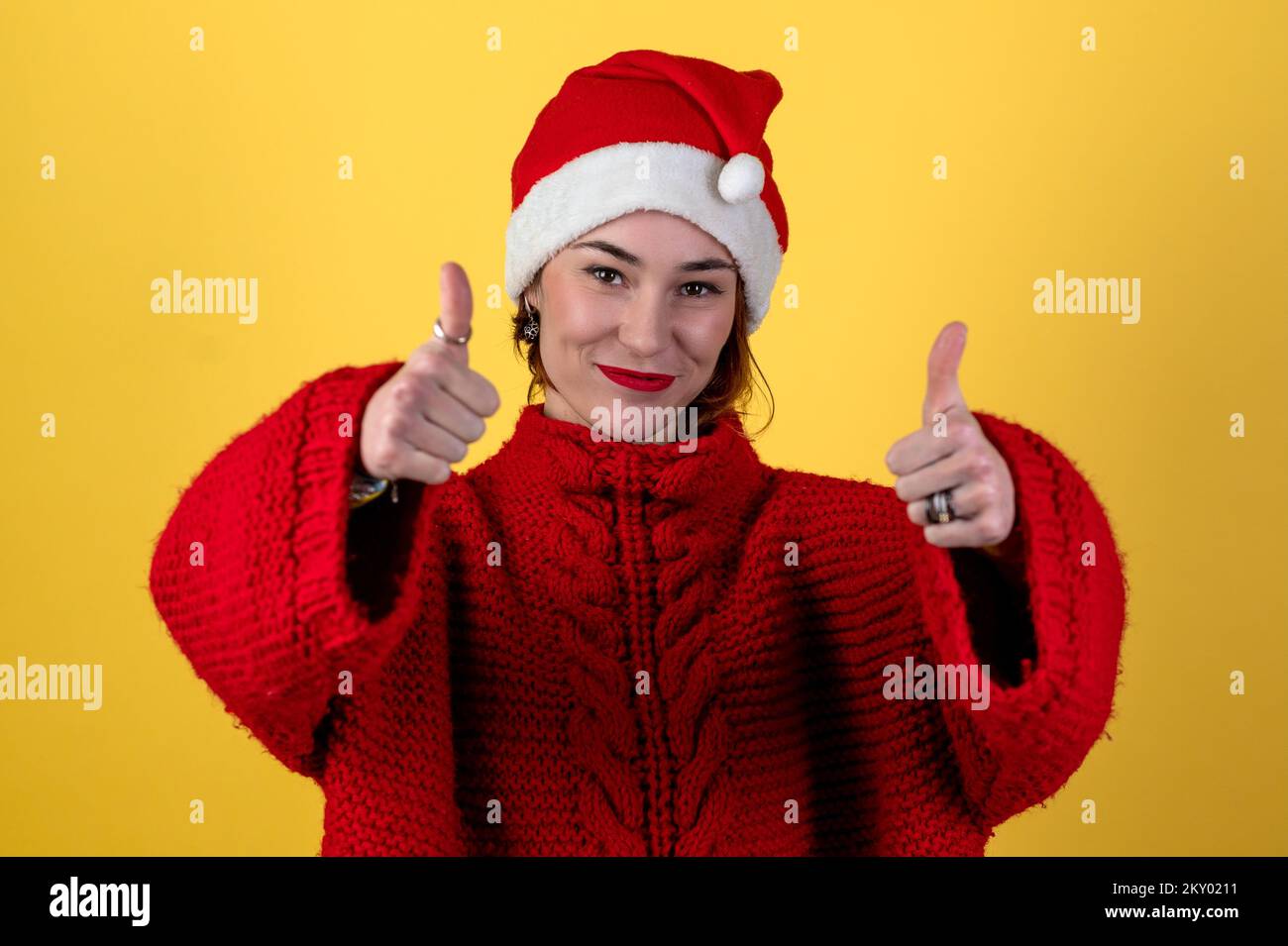 Young positive woman in christmas santa hat isolated on yellow ...