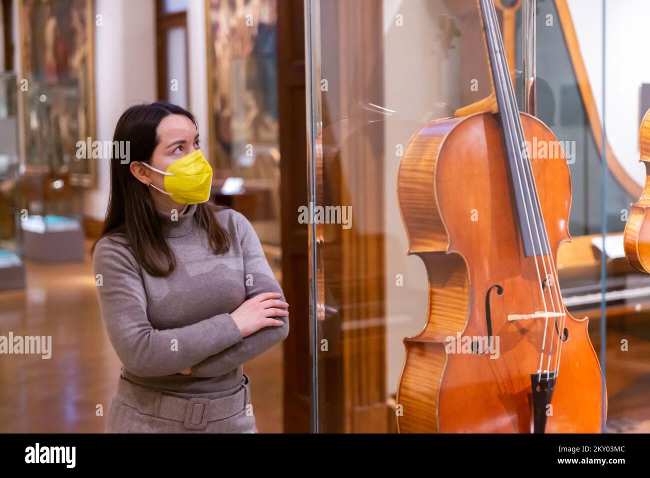 Woman in mask viewing collections of ancient musical instruments in ...