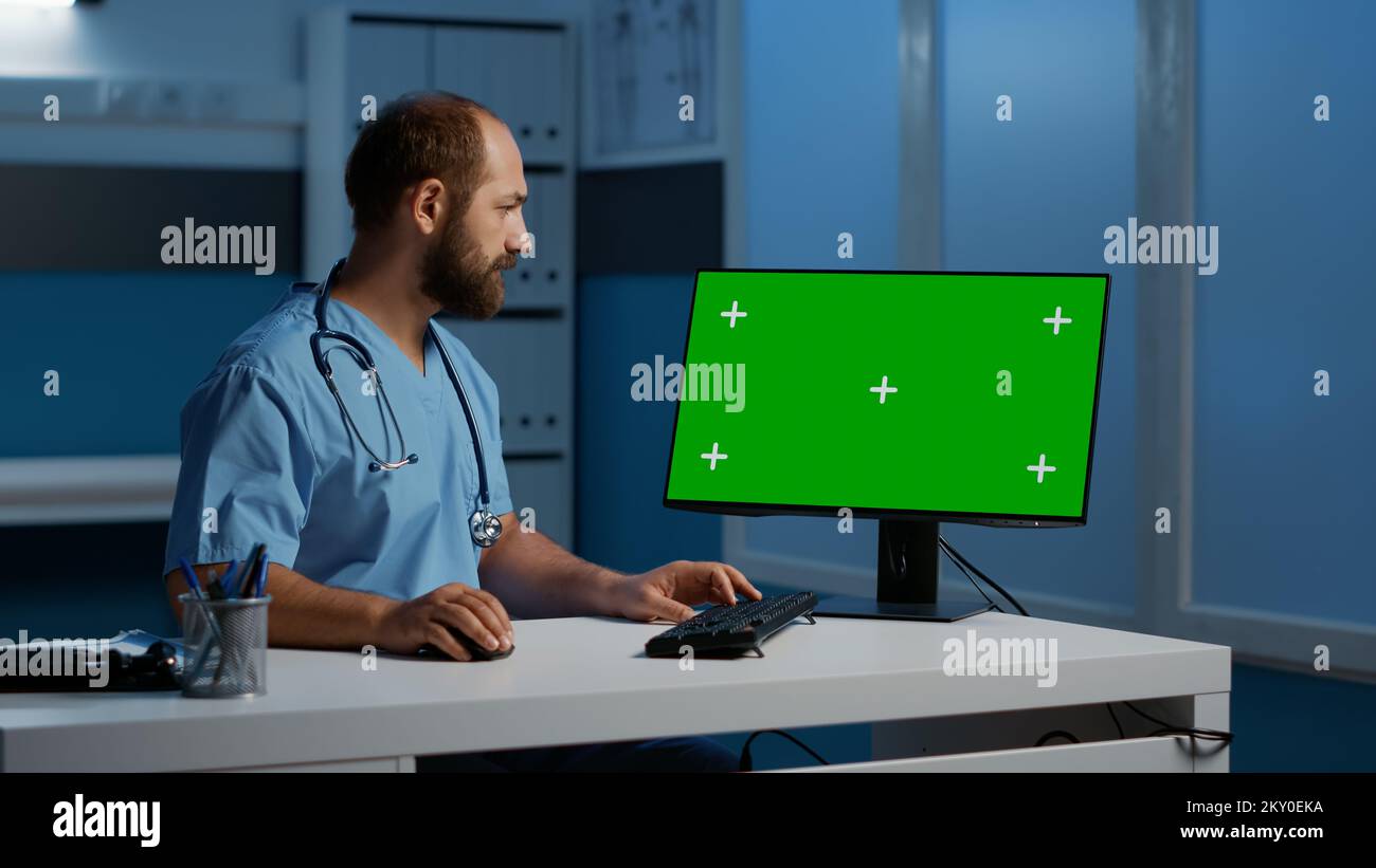 Medical assistant sitting at desk typing patient disease report on ...