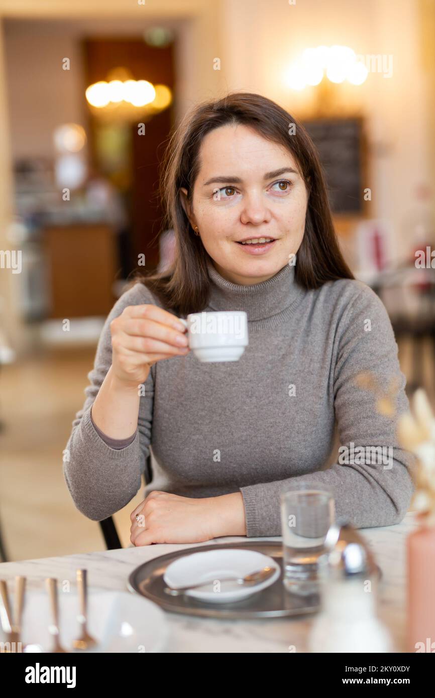 Brunette sitting in cozy cafe with cup of coffee Stock Photo - Alamy