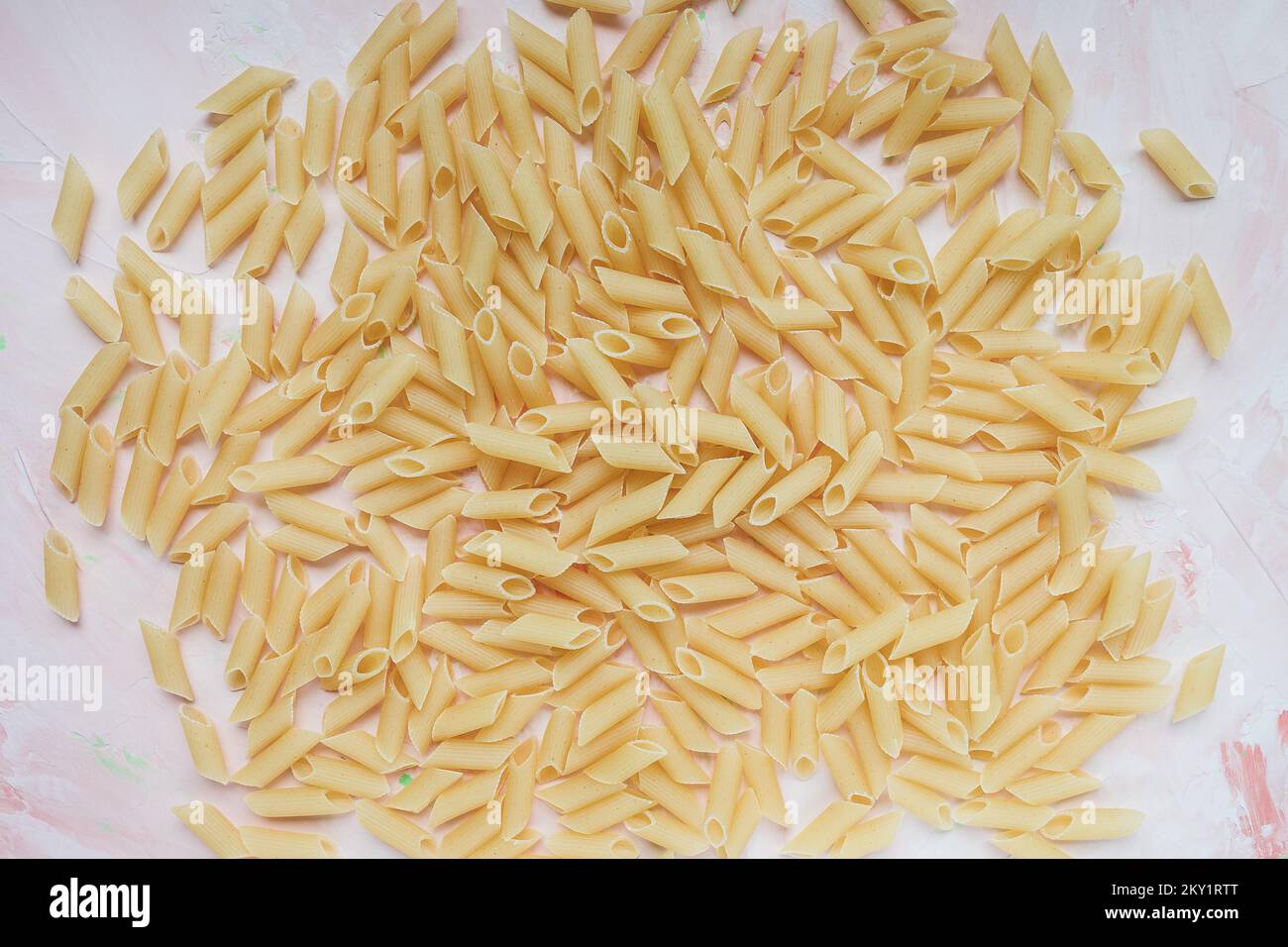 Pile of raw traditional Italian penne pasta on piink background ...