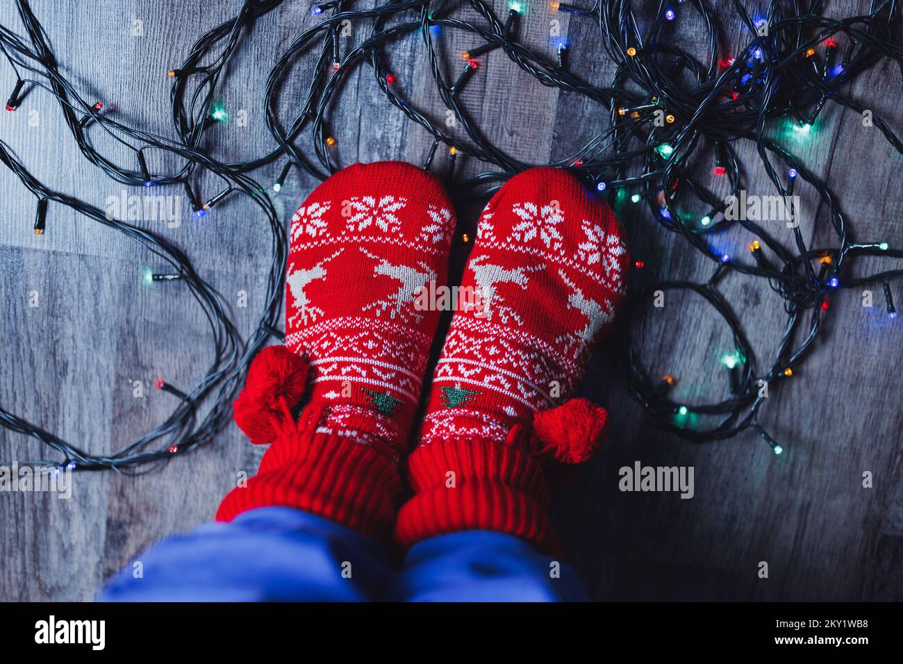 Tangled Christmas lights down on floor at feet in red Christmas socks ...