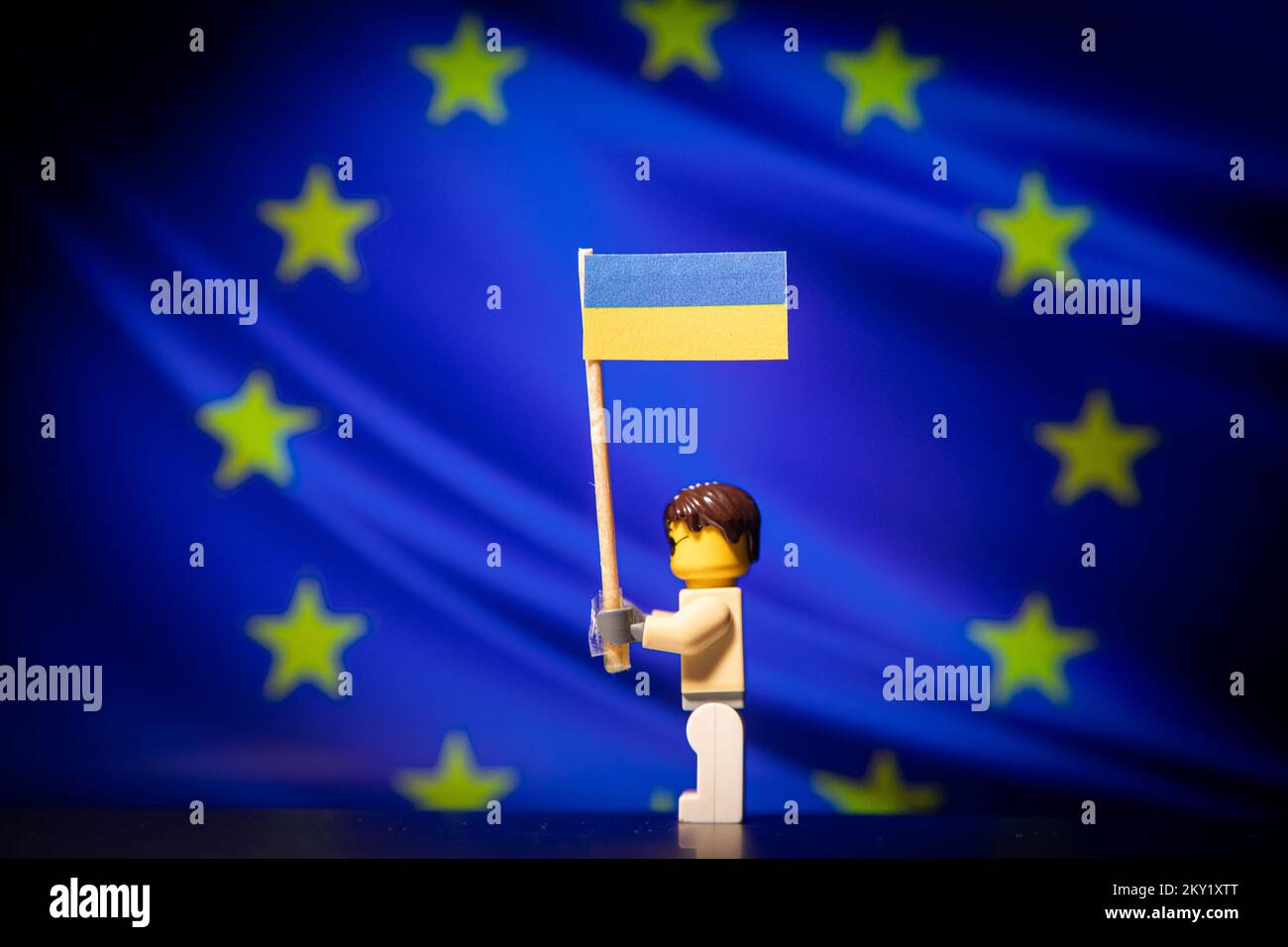 A Lego minifigure holds a flag of Ukraine in front of Flag of Europe in ...