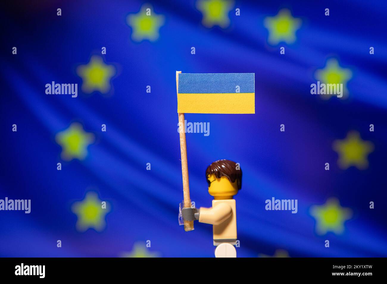 A Lego minifigure holds a flag of Ukraine in front of Flag of Europe in ...