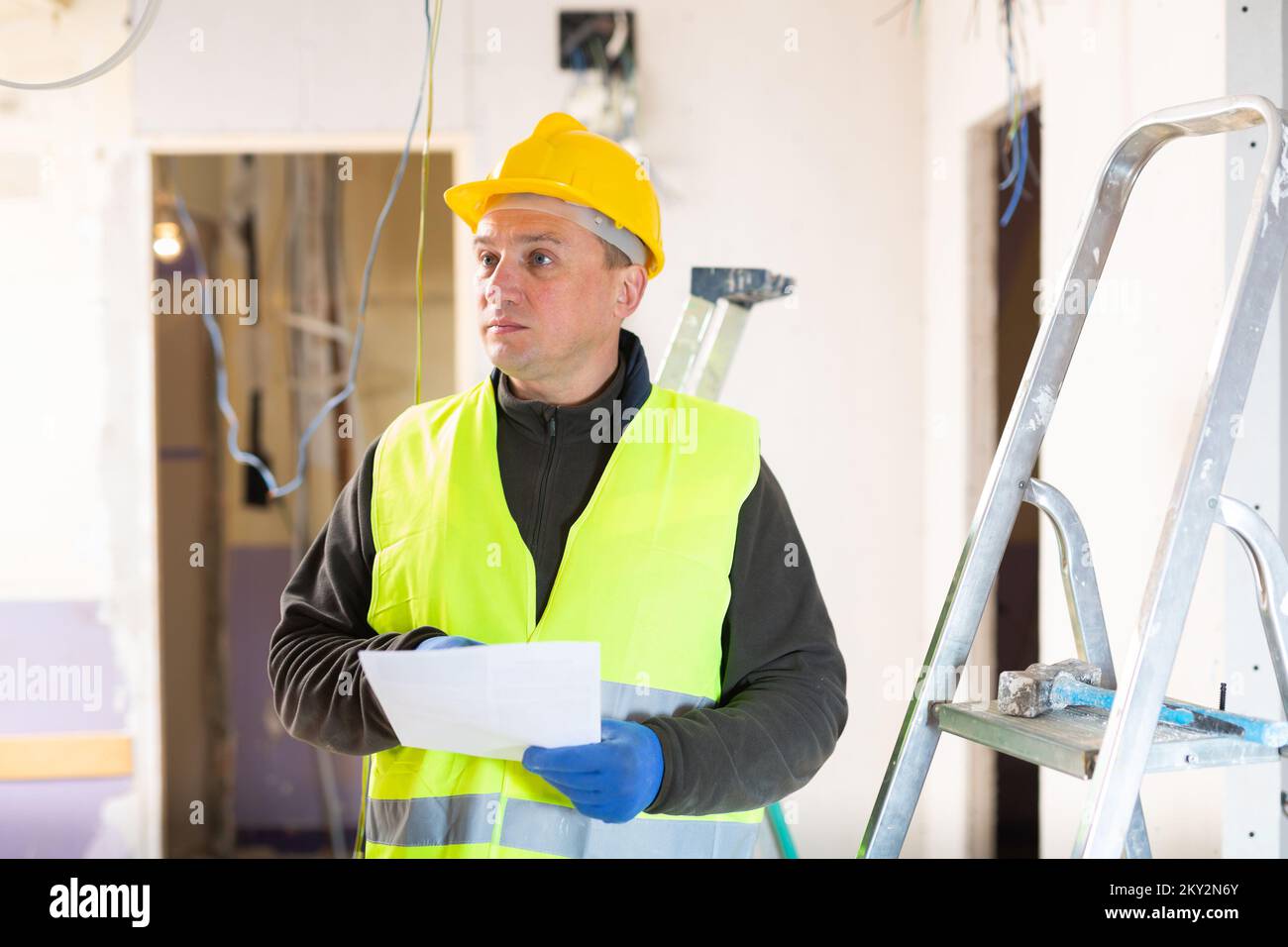 Male contractor looking at room and determining scope of building work ...