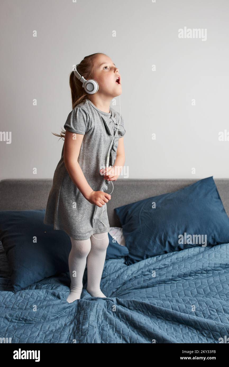 Little girl singing holding headphones cord imitating herself a real ...