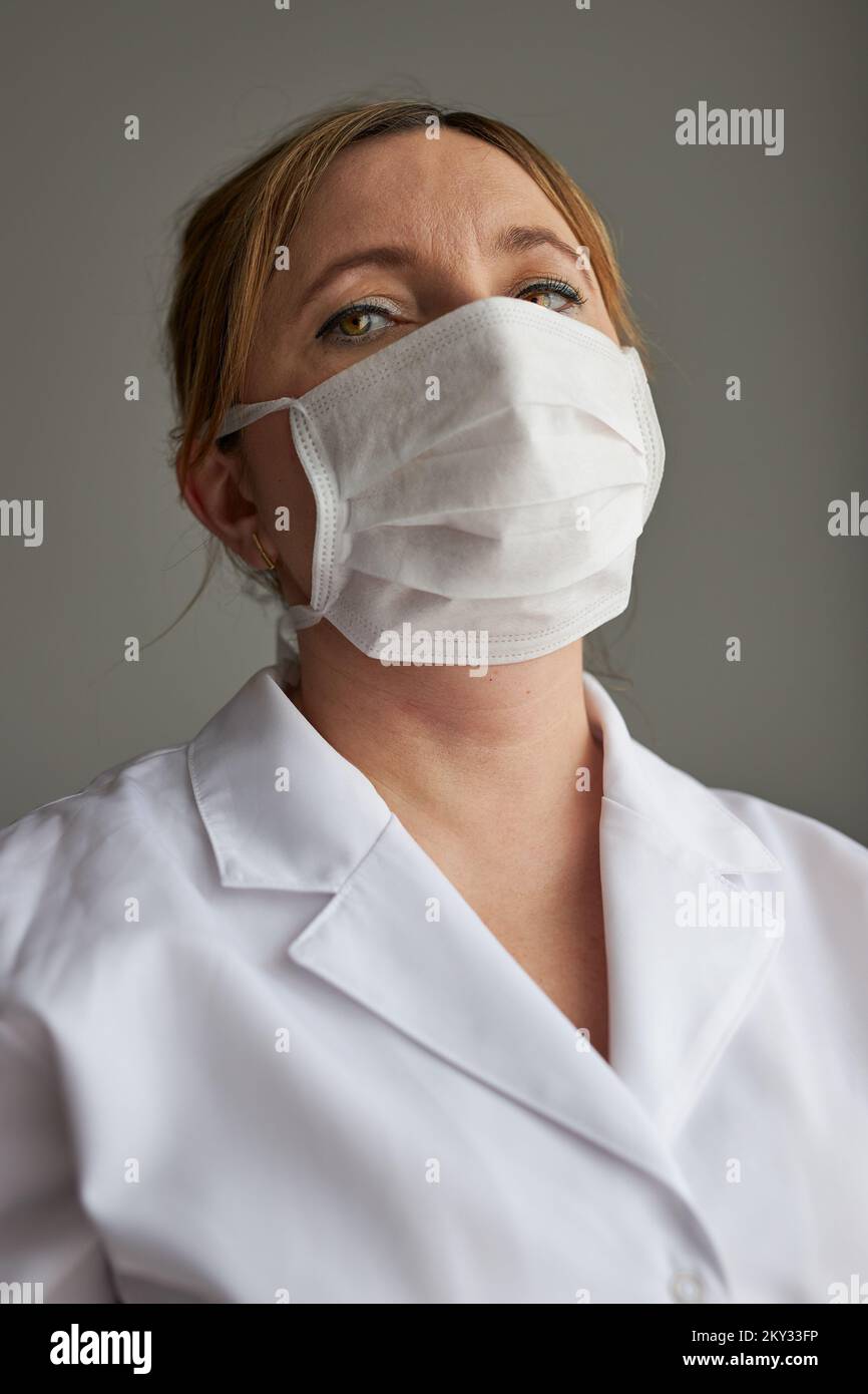Doctor with face covered with mask. Portrait of young woman wearing the ...