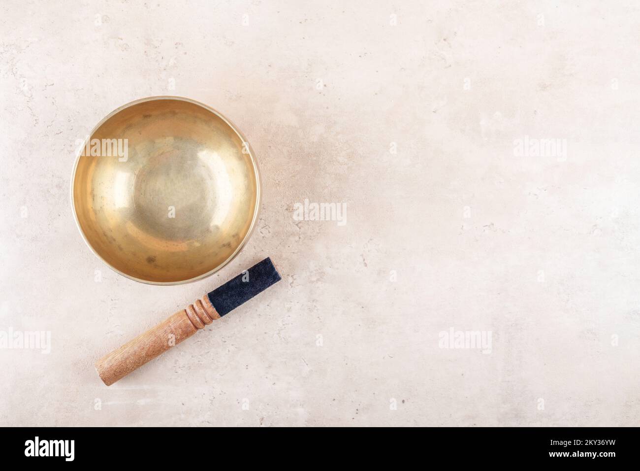 Tibetan singing bowl with stick used during mantra meditations on beige ...