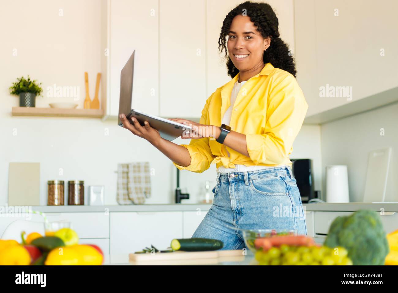 Searching for new recipes. Happy black woman holding and using laptop ...