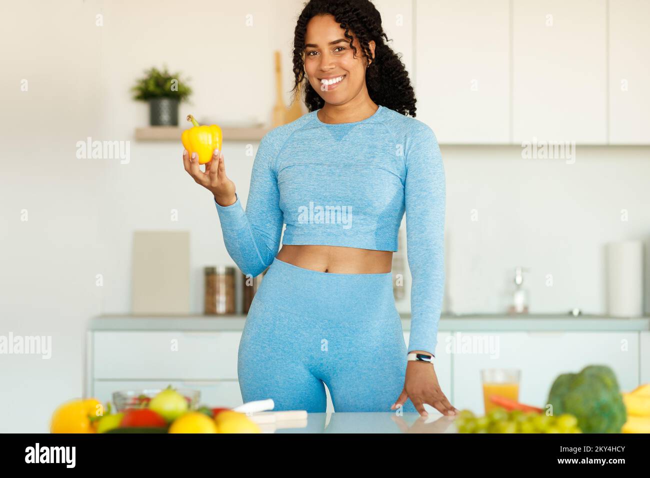 Happy african american lady in sportswear cooking fresh salad and ...