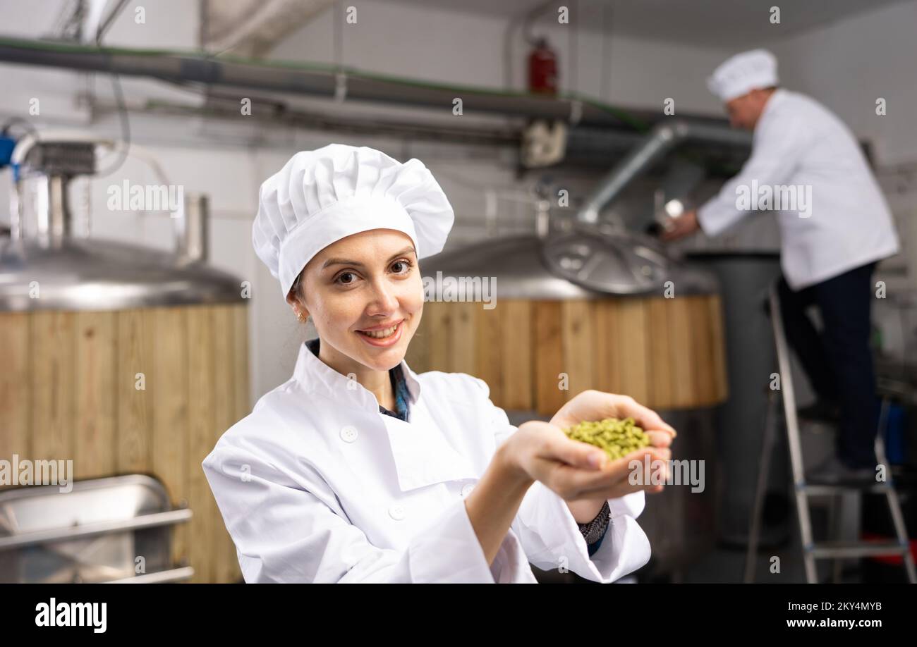 Smiling female brewmaster holding handful of pelletized hops Stock ...