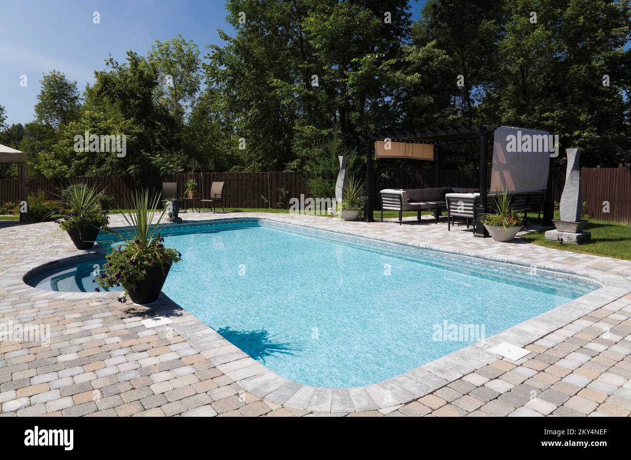 In-ground swimming pool and patio furniture in landscaped residential ...