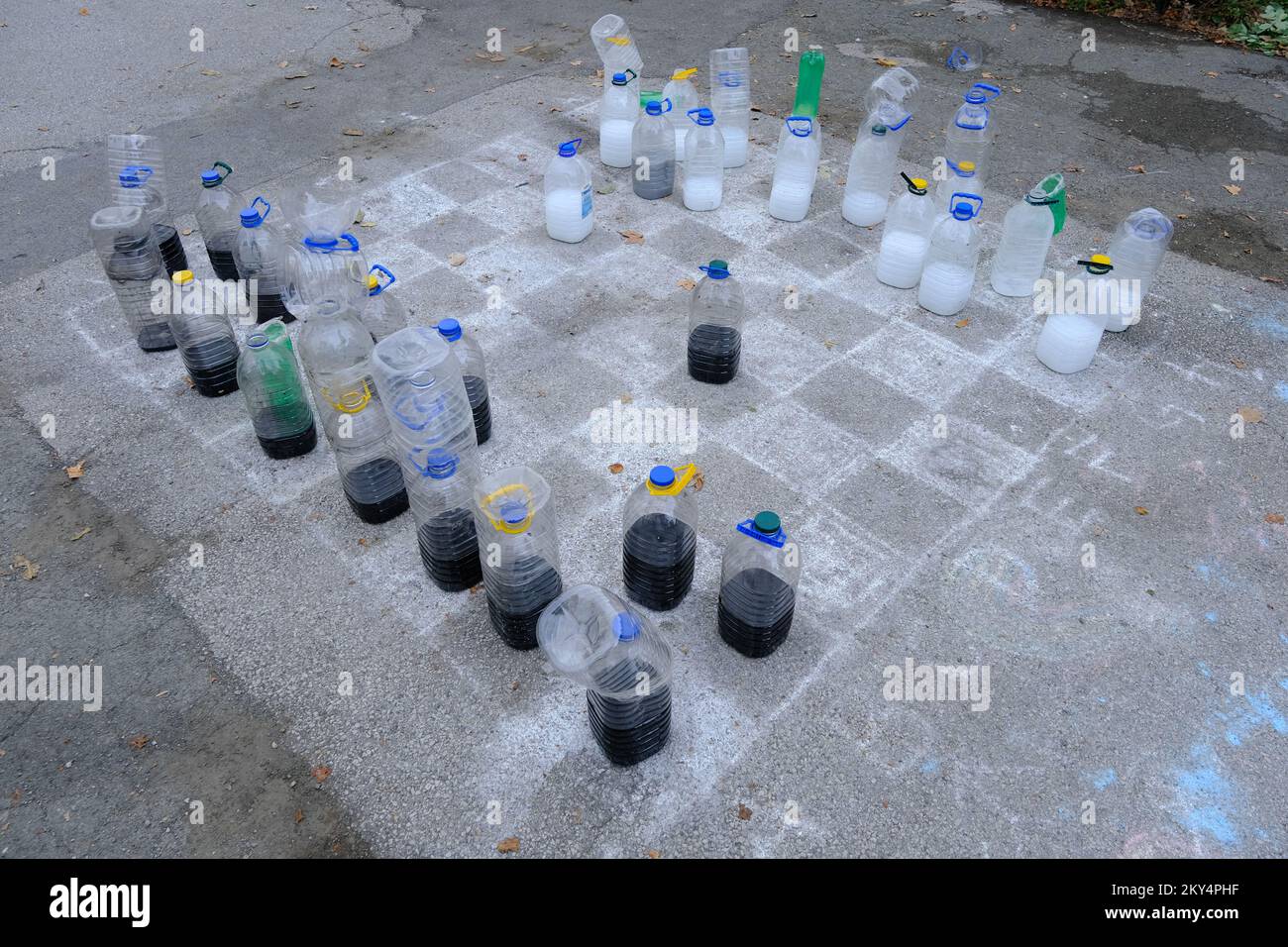 Big chess board of chalk with chess pieces made of plastic bottles seen ...