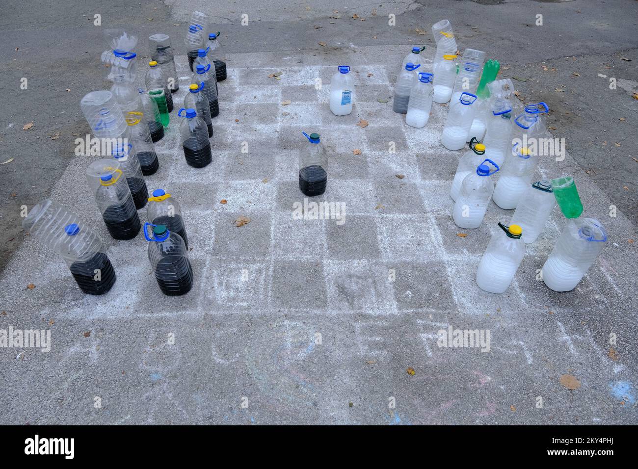 Big chess board of chalk with chess pieces made of plastic bottles seen ...