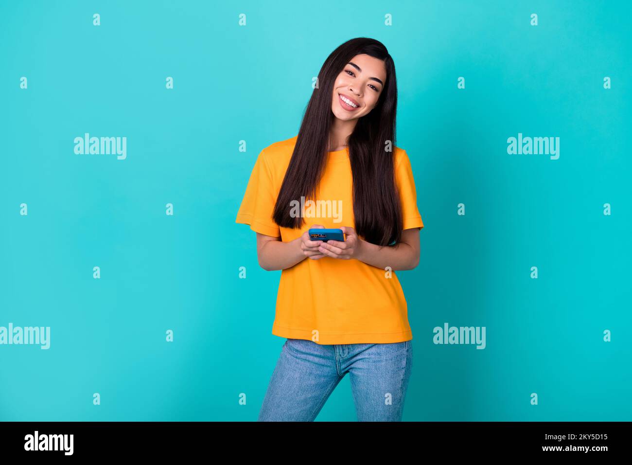 Photo of optimistic young lady hold telephone wear orange t-shirt jeans ...