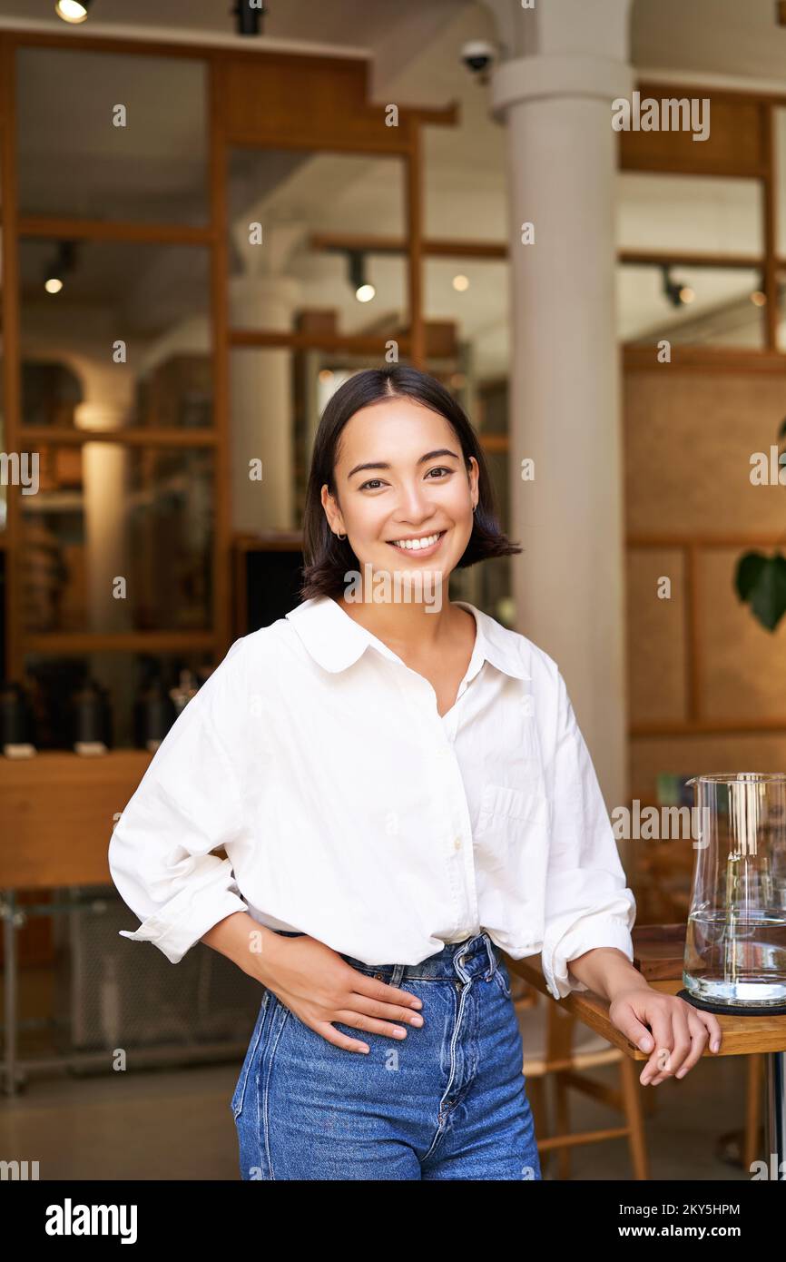 Smiling asian manager, confident woman standing near restaurant ...