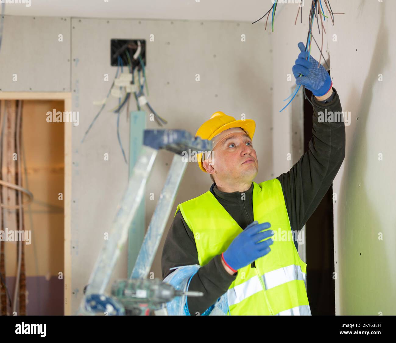 Experienced friendly electrician laying electric wires in building ...