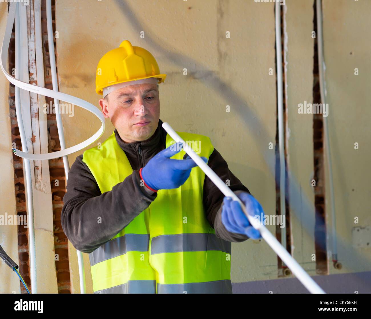 Plumber prepares plastic pipes for installation in building under ...