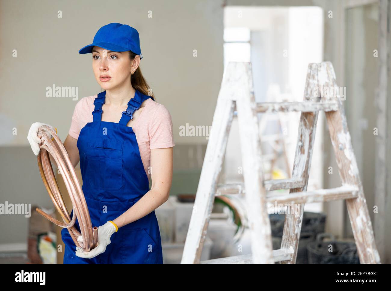 Female builder carrying conduit at renovating object Stock Photo - Alamy