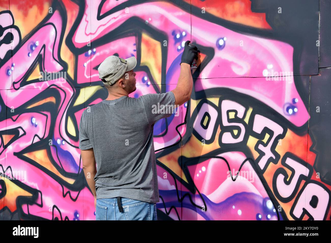 Young caucasian male graffiti artist drawing big street art painting in ...