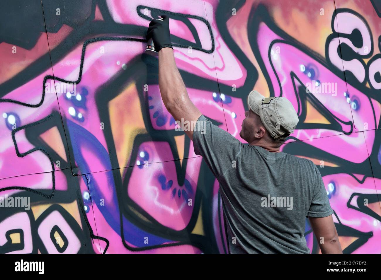 Young caucasian male graffiti artist drawing big street art painting in ...