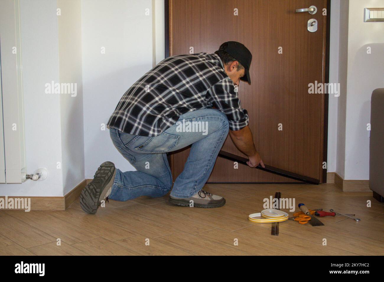 Image of a handyman installing a draft excluder on his front door ...
