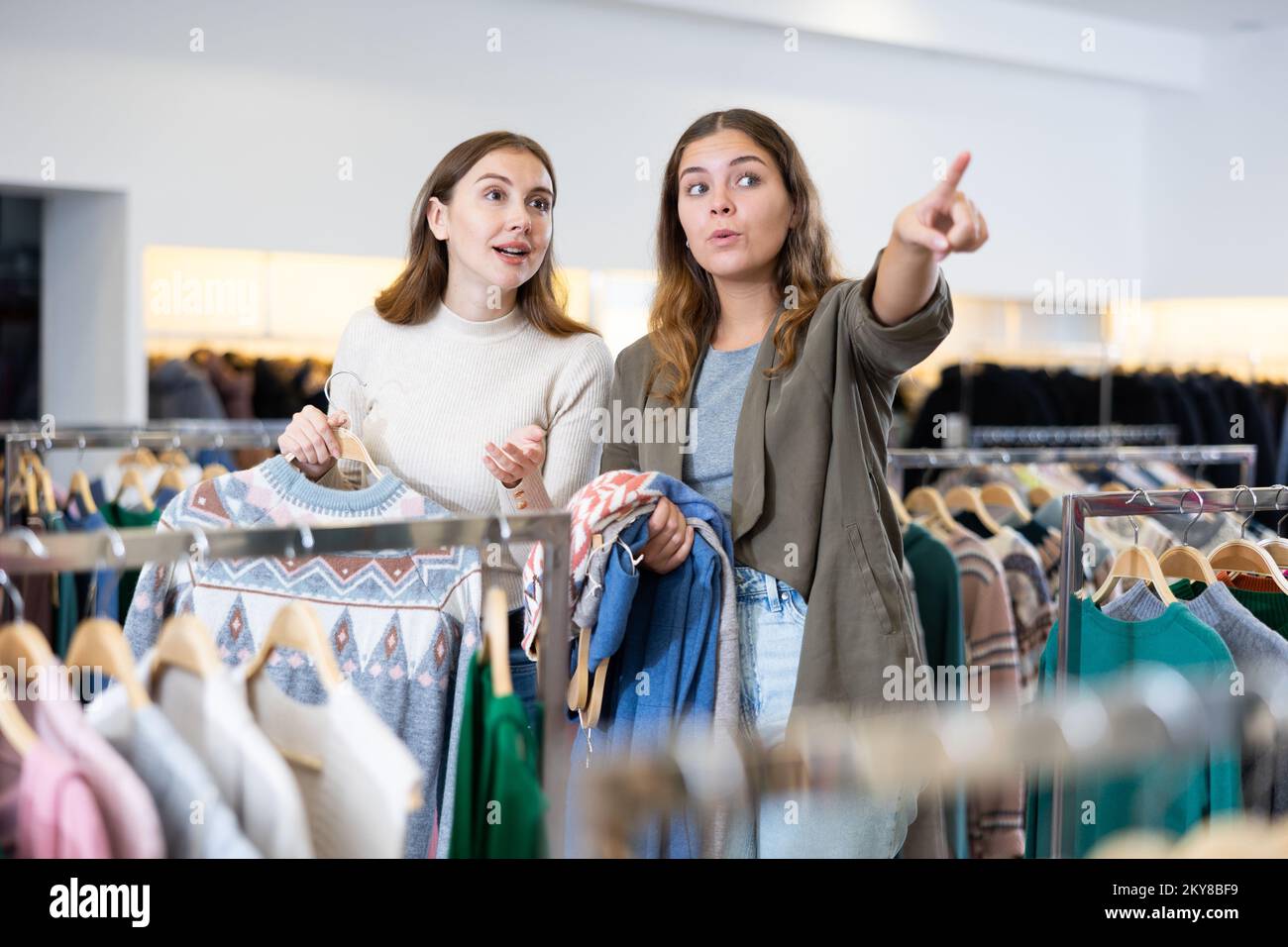 Cheerful young women pointing on clothes far away, spending time in a ...