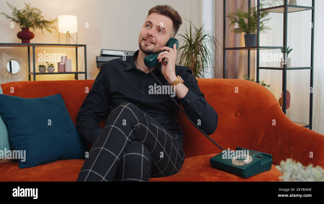 Portrait of man making wired telephone conversation with friends ...