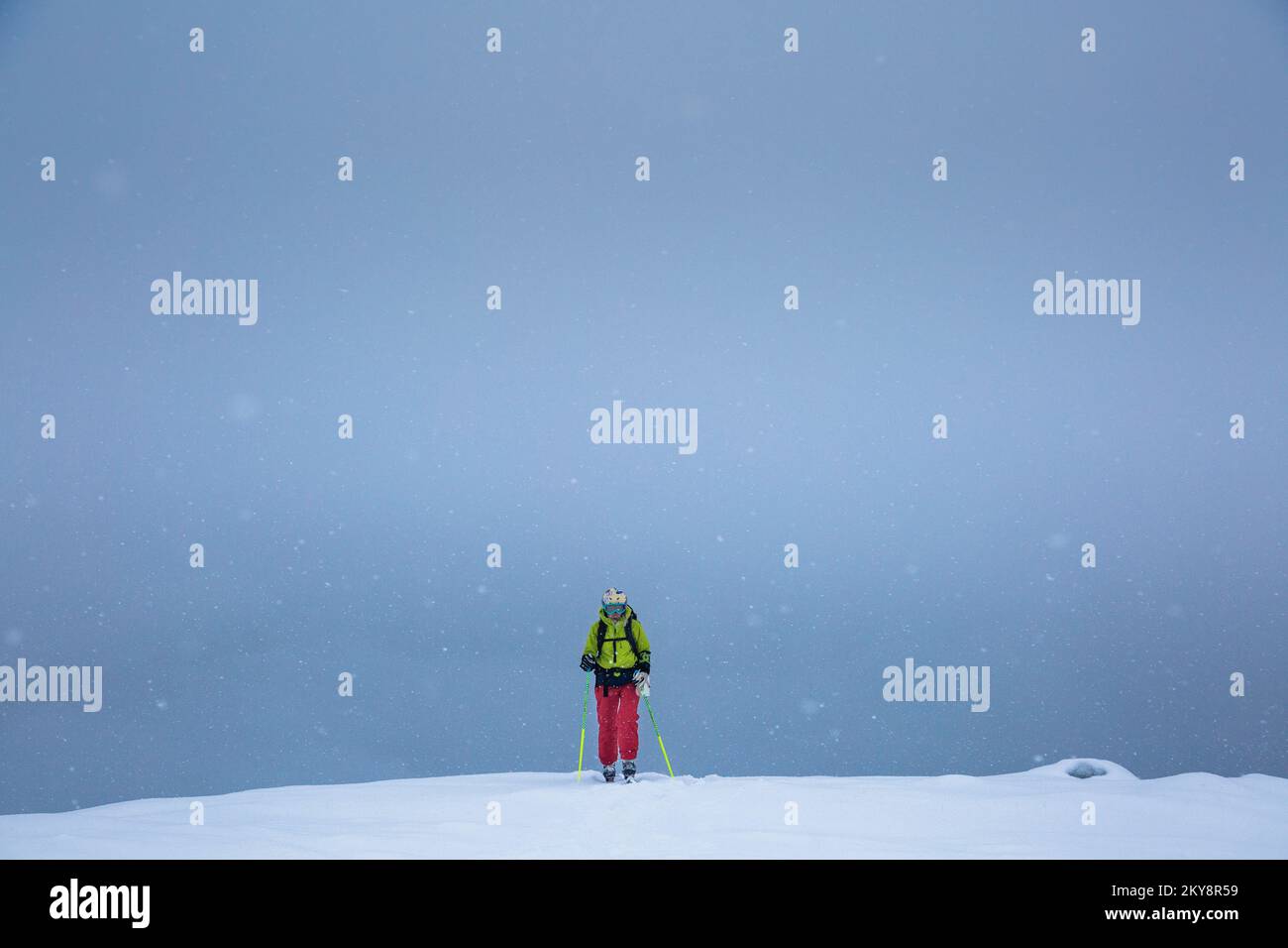 An active female skitourer hikes in a foggy snowstorm in a backcountry ...