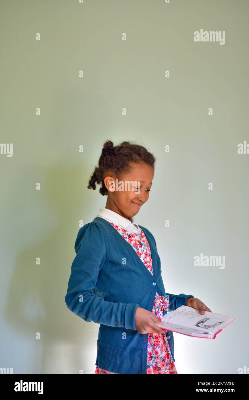 little girl standing up reading a book for school Stock Photo - Alamy