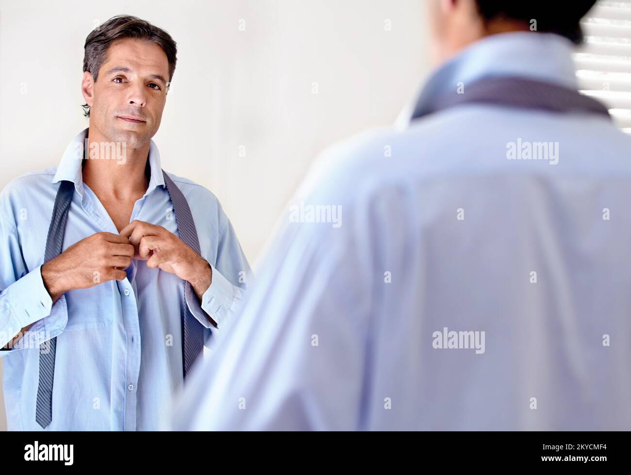 Getting ready for work in front of the mirror. A mature businessman looking at his reflection in ...