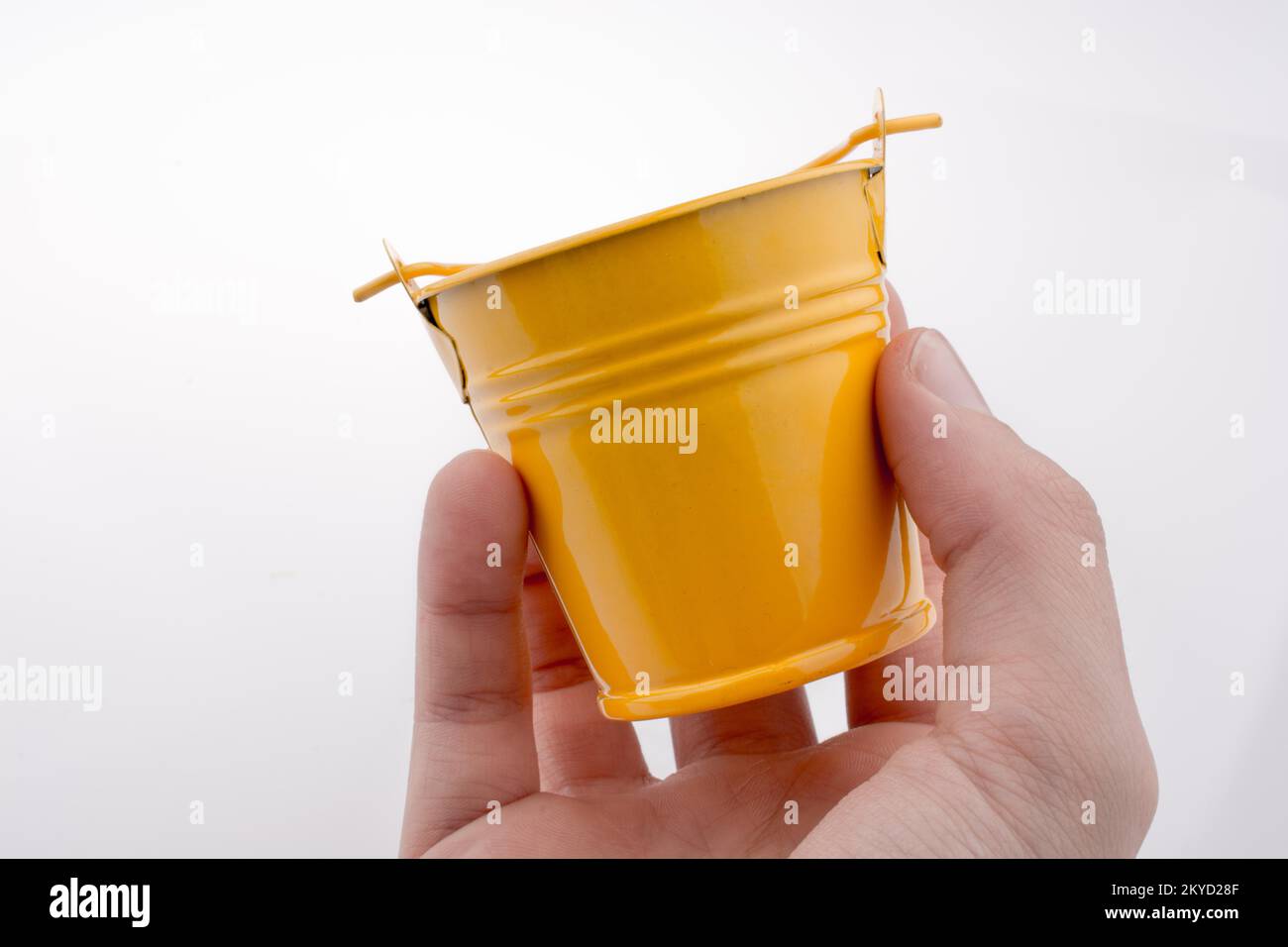 Hand holding a yellow bucket on a white background Stock Photo - Alamy