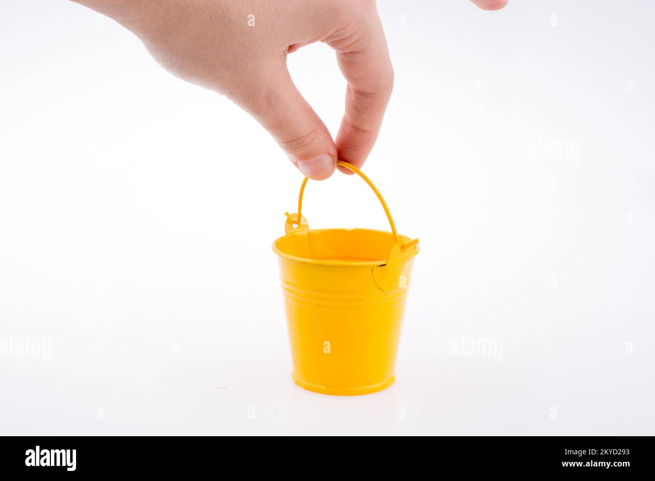 Hand holding a yellow bucket on a white background Stock Photo - Alamy