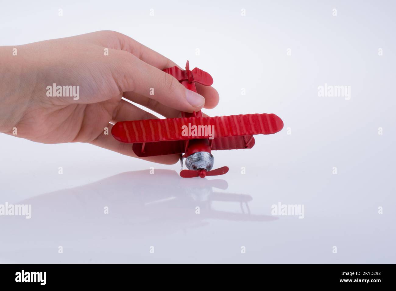 Hand holding a red toy plane on a white background Stock Photo - Alamy