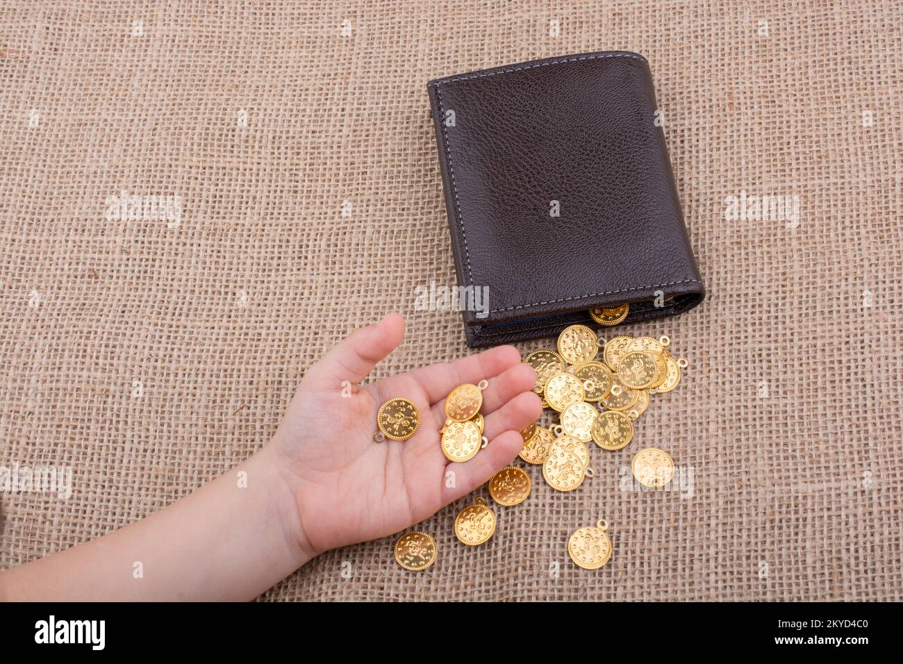Wallet and plenty of fake gold coins in hnad Stock Photo - Alamy