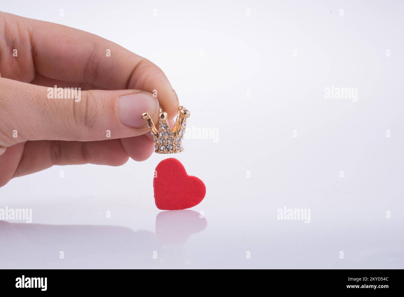 Hand holding crown near a red heart on a white background Stock Photo ...