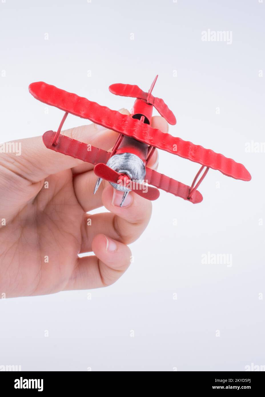 Hand holding a red toy plane on a white background Stock Photo - Alamy