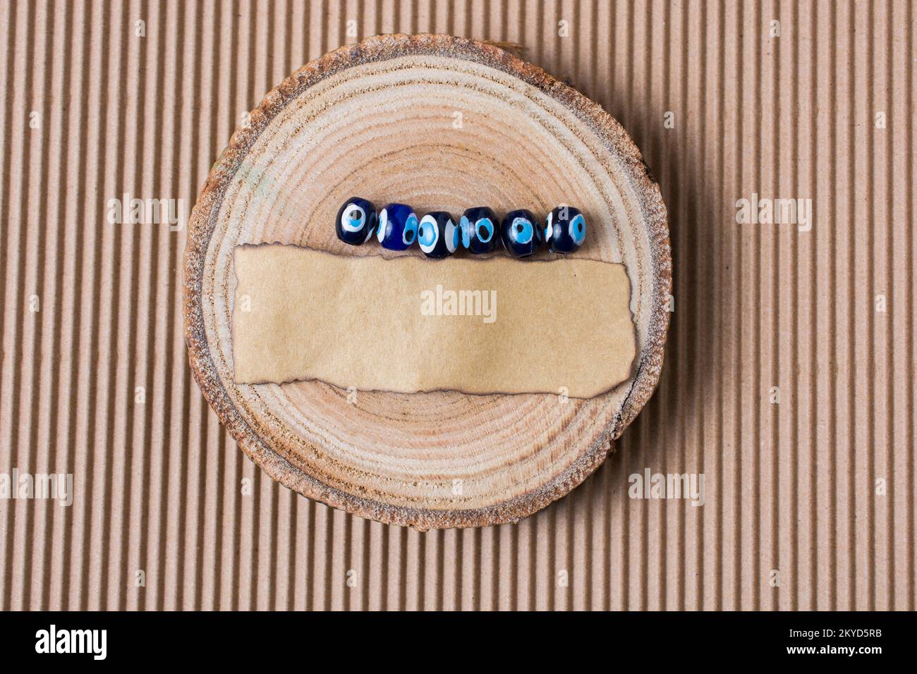 Evil eye beads and piece of burnt paper on wood log Stock Photo - Alamy
