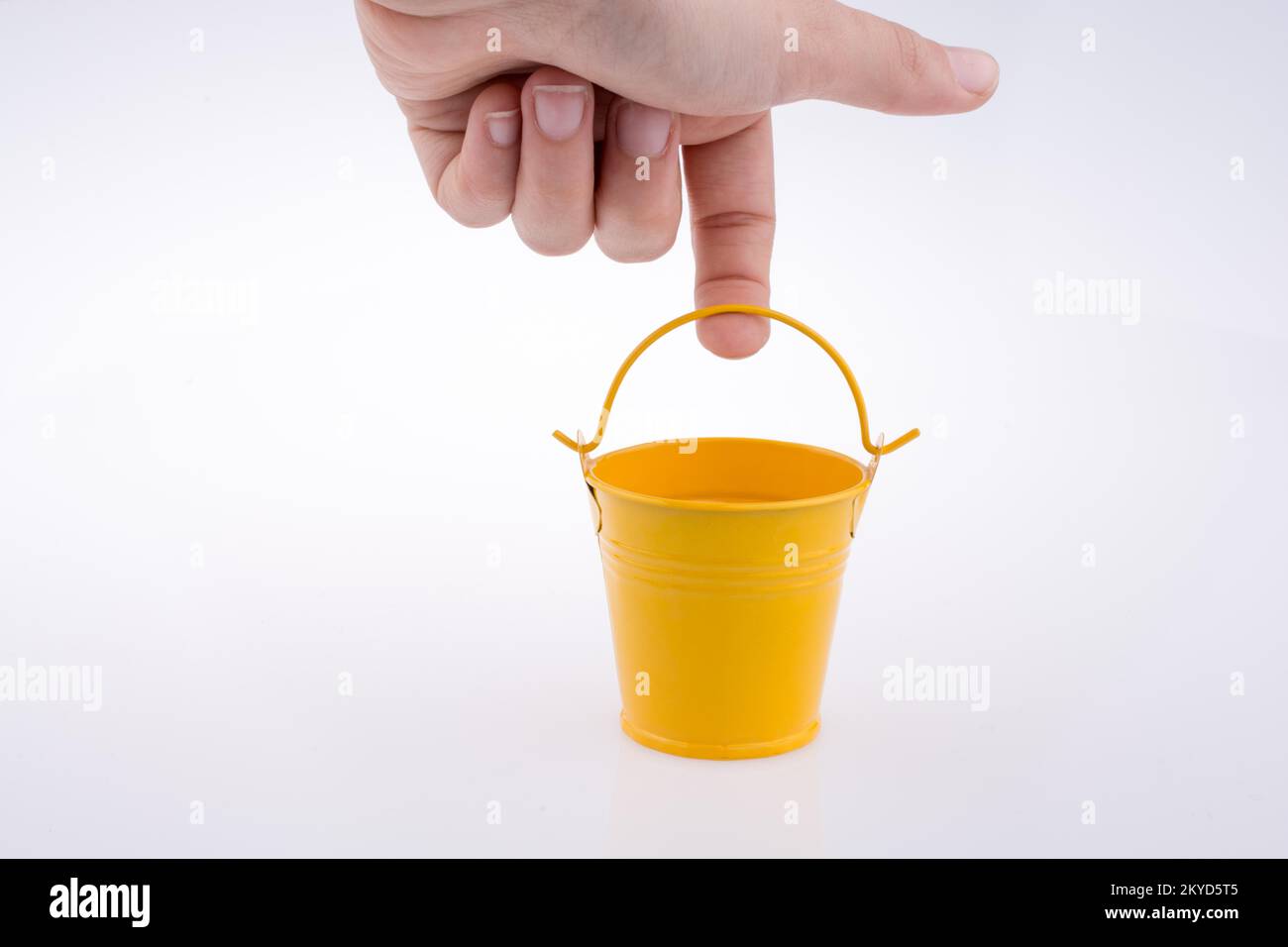 Hand holding a yellow bucket on a white background Stock Photo - Alamy