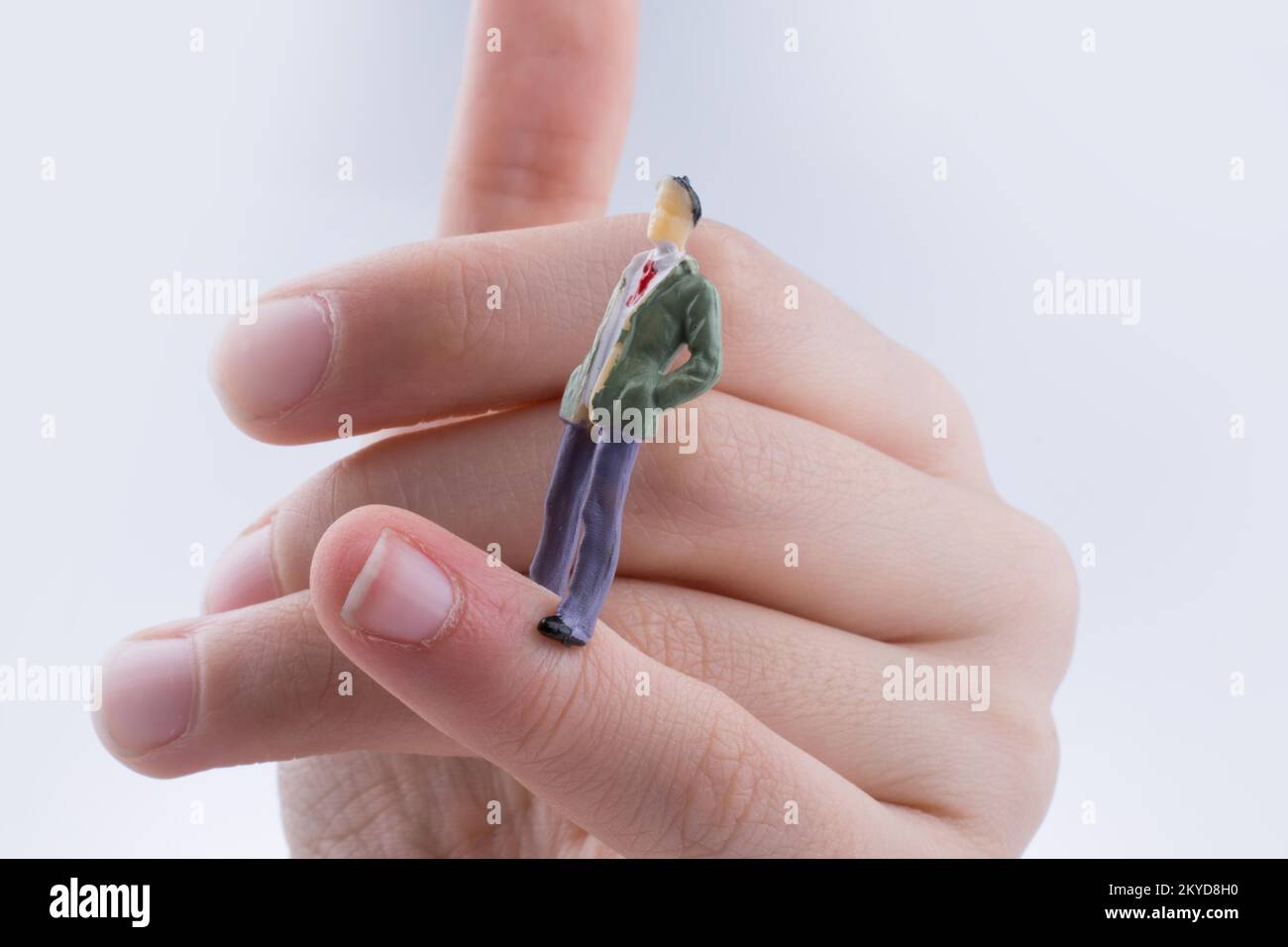 Hand holding a human figure on a white background Stock Photo - Alamy