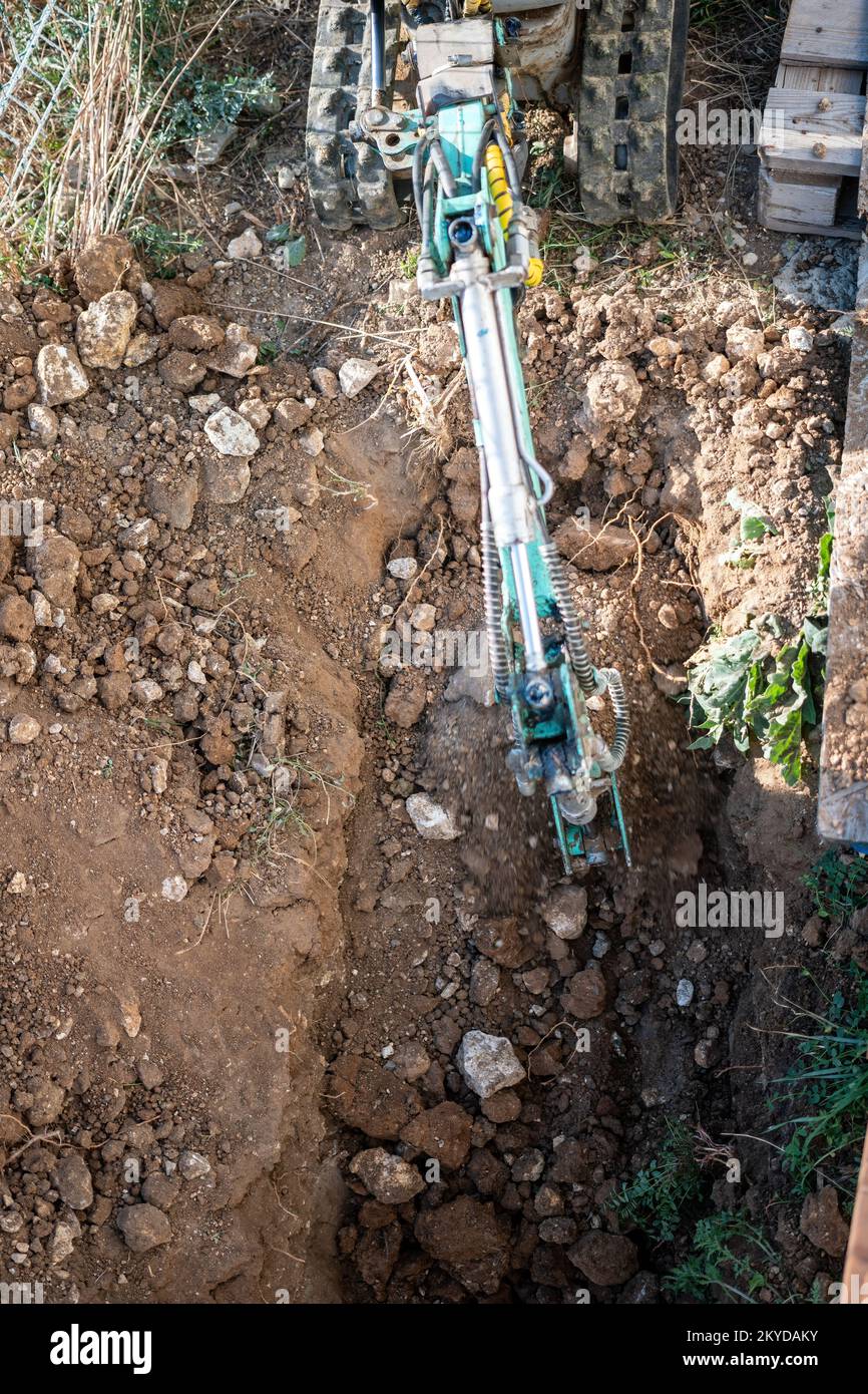 Mini excavator digs a trench to lay pipes. Close up of an excavator ...