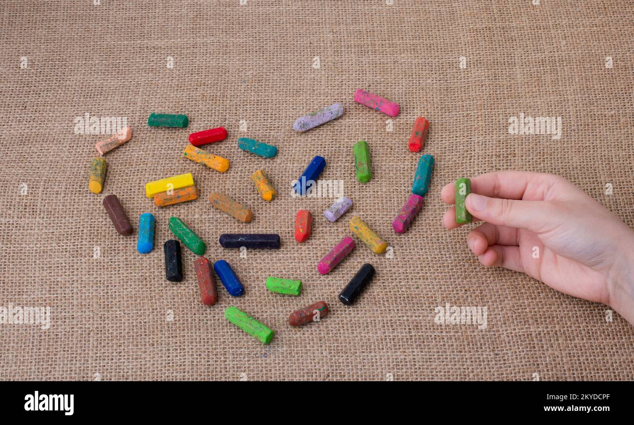 Hand holding a crayon by crayons forming a heart shape Stock Photo - Alamy