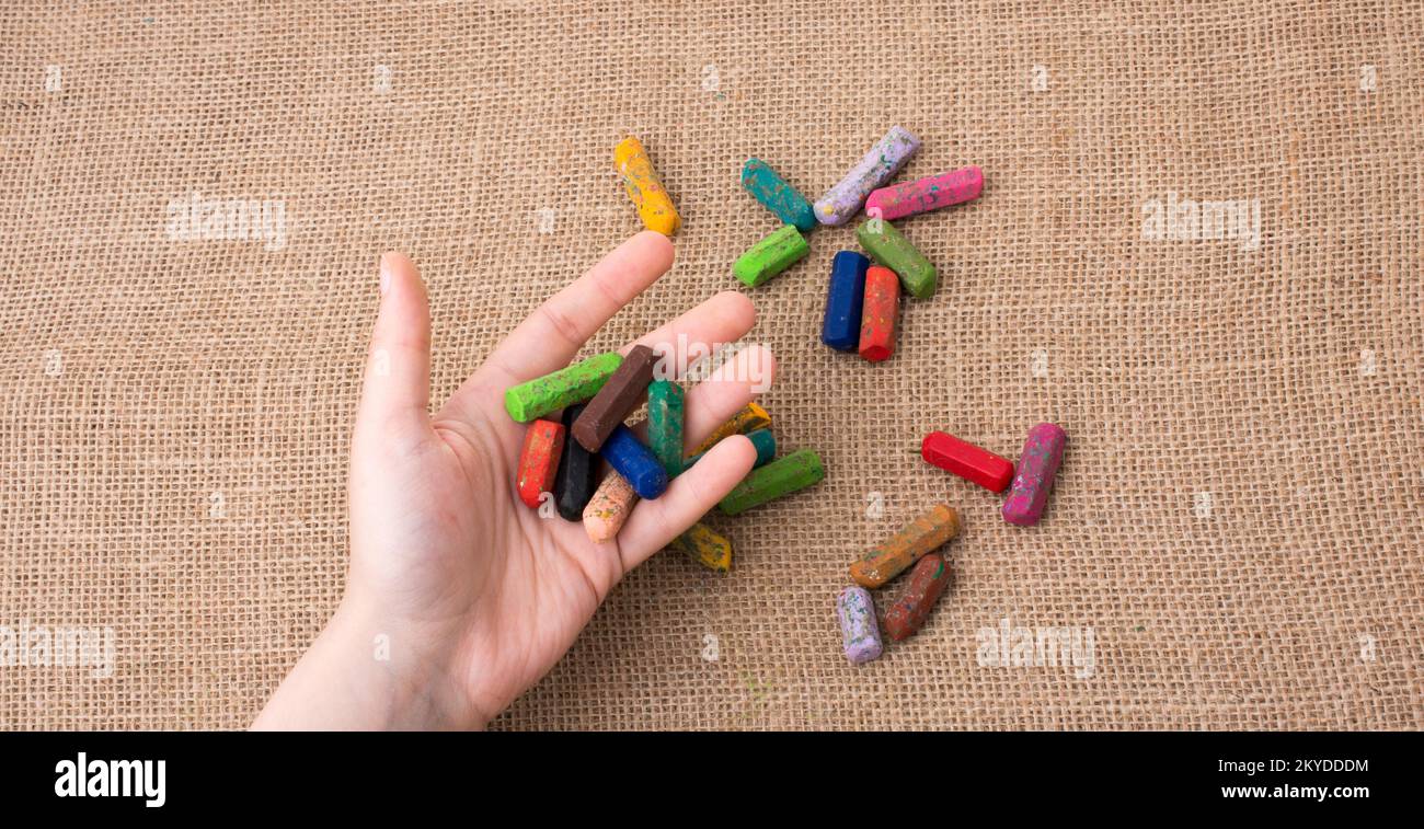 Used color crayons and a hand holding some Stock Photo - Alamy