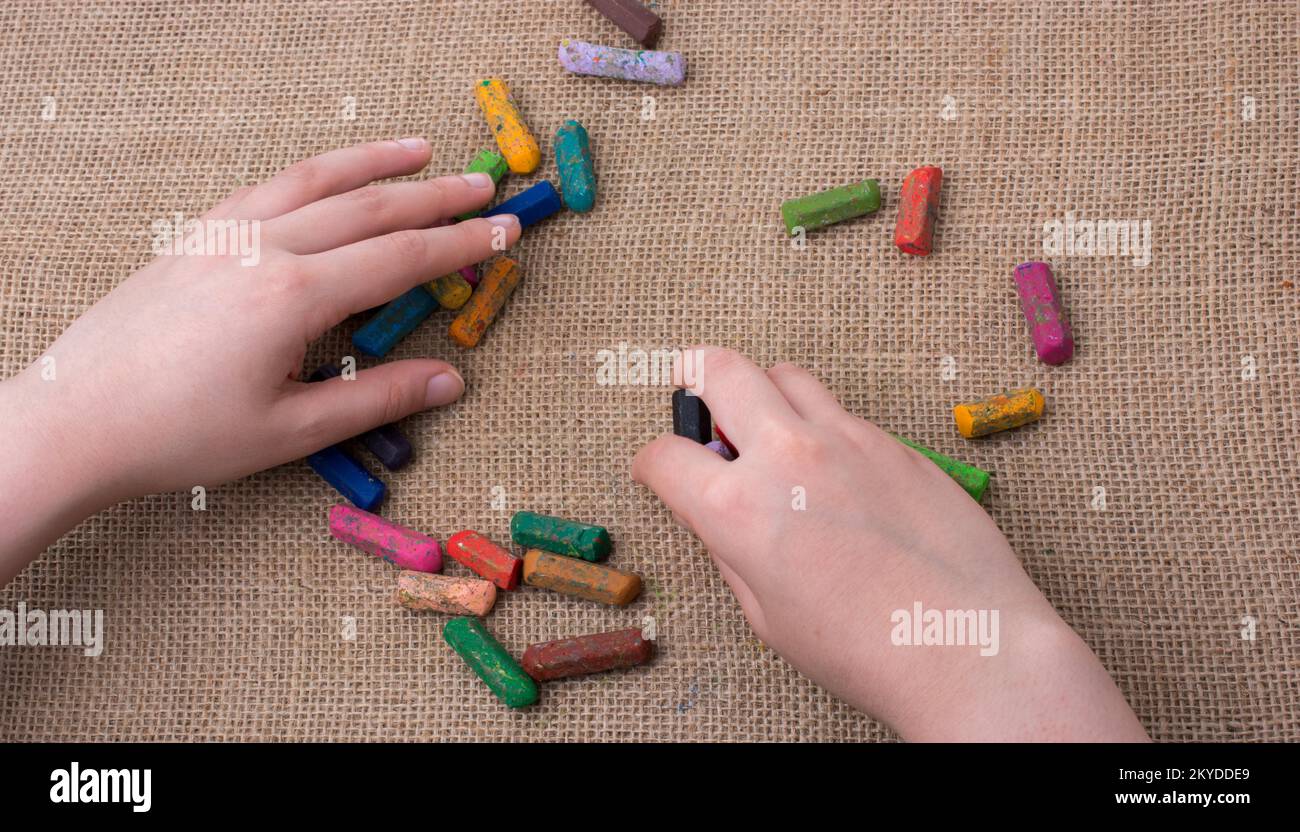 Used color crayons and a hand giving out some Stock Photo - Alamy