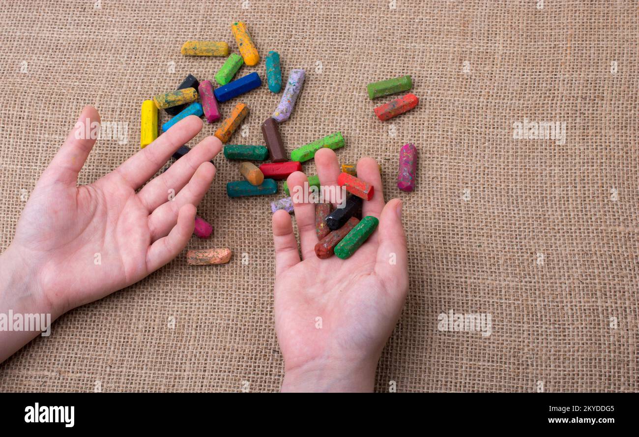 Used color crayons and a hand holding some Stock Photo - Alamy