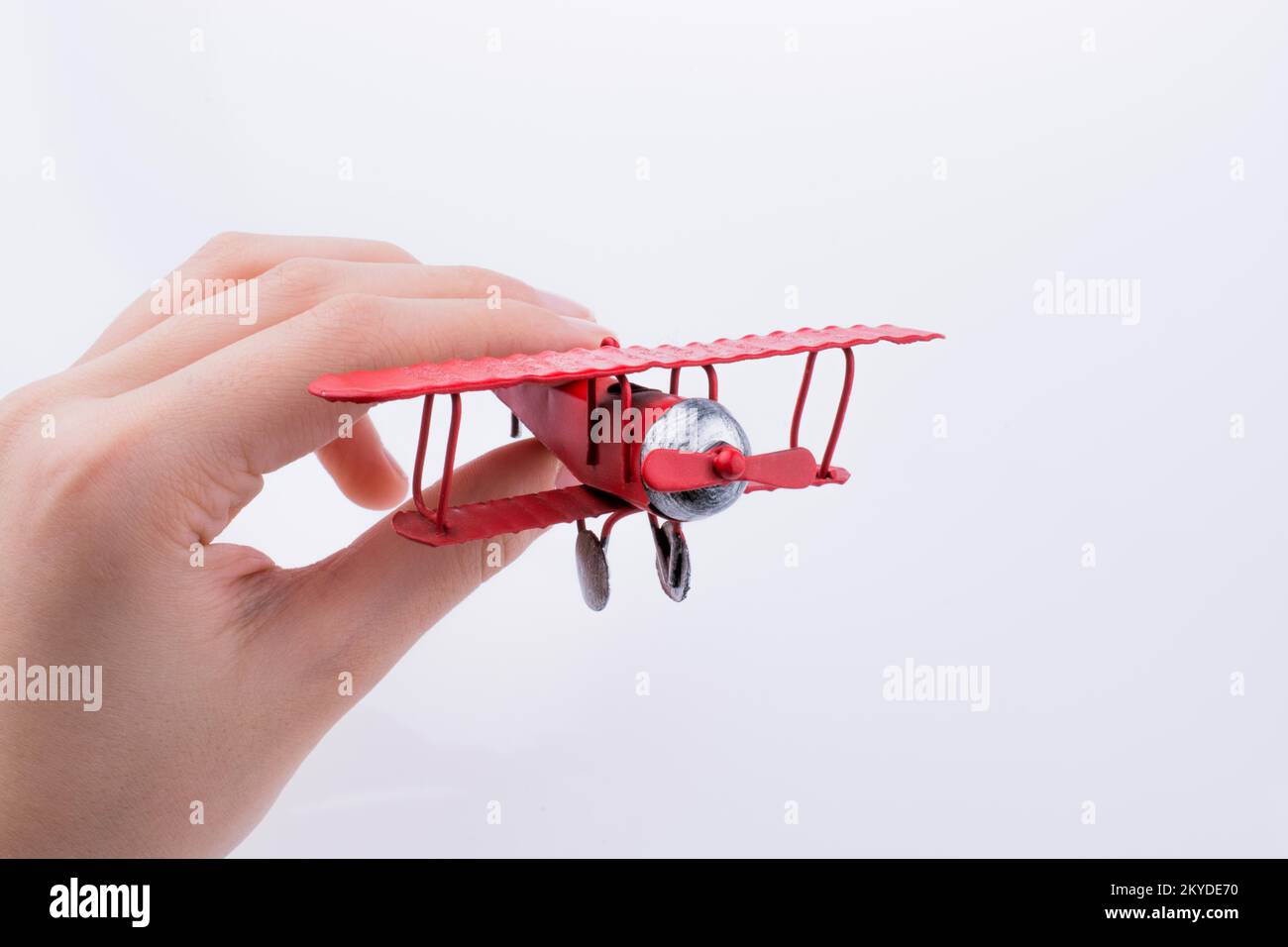 Hand holding a red toy plane on a white background Stock Photo - Alamy