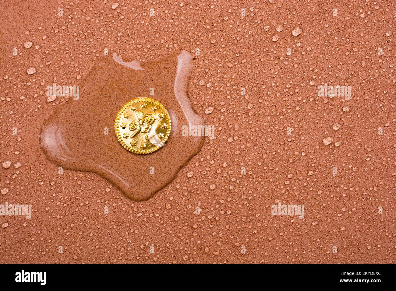 Fake gold coin covered with water drop in close-up view Stock Photo - Alamy
