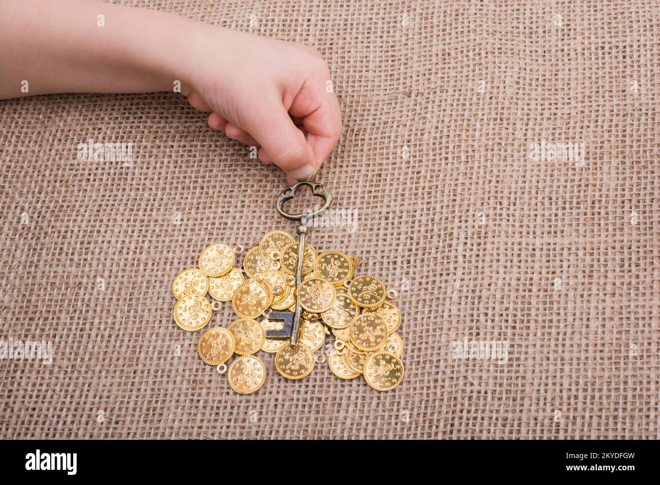Hand holding a retro styled key over fake gold coins Stock Photo - Alamy