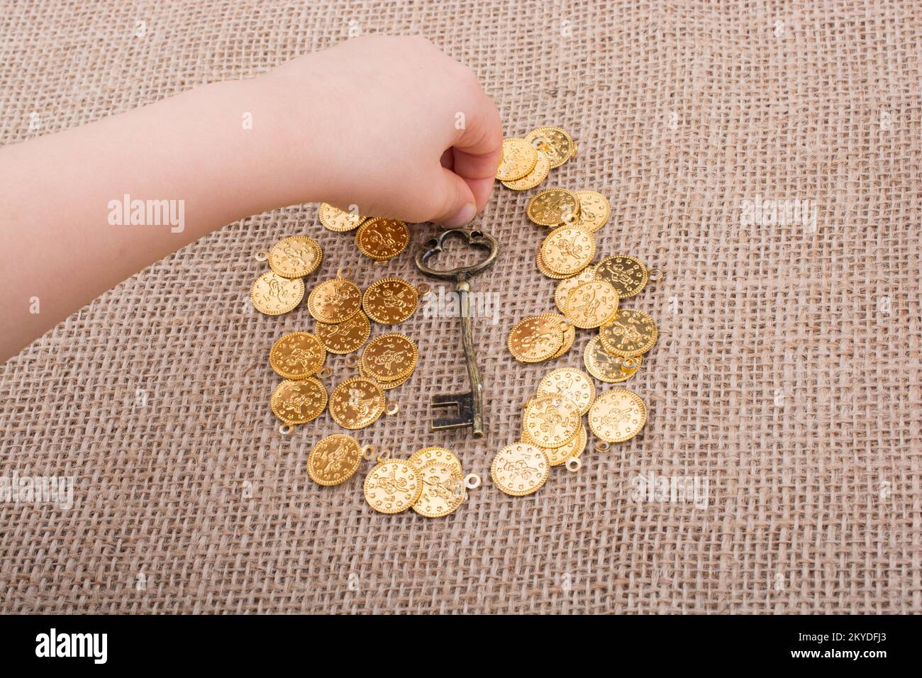 Hand holding a retro styled key over fake gold coins Stock Photo - Alamy