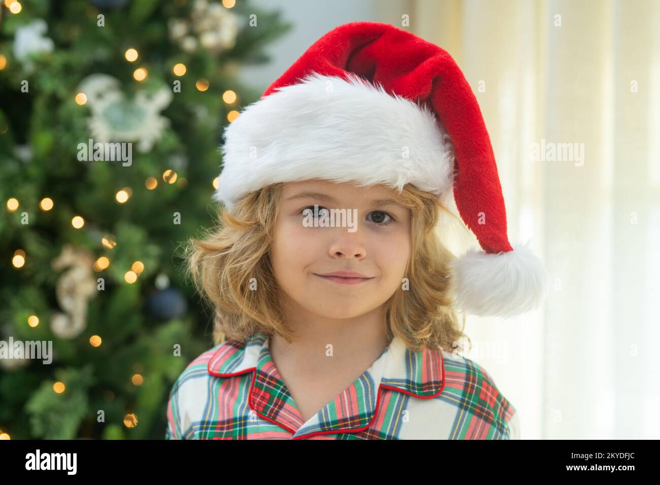 Happy child in santa hat near christmas tree at home Stock Photo - Alamy